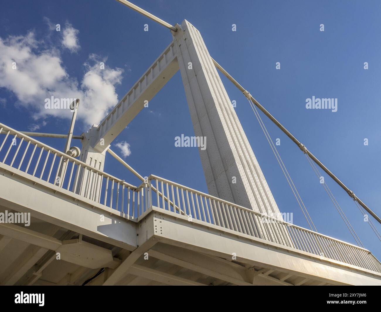 Detail of a modern white metal bridge in front of a bright blue sky ...