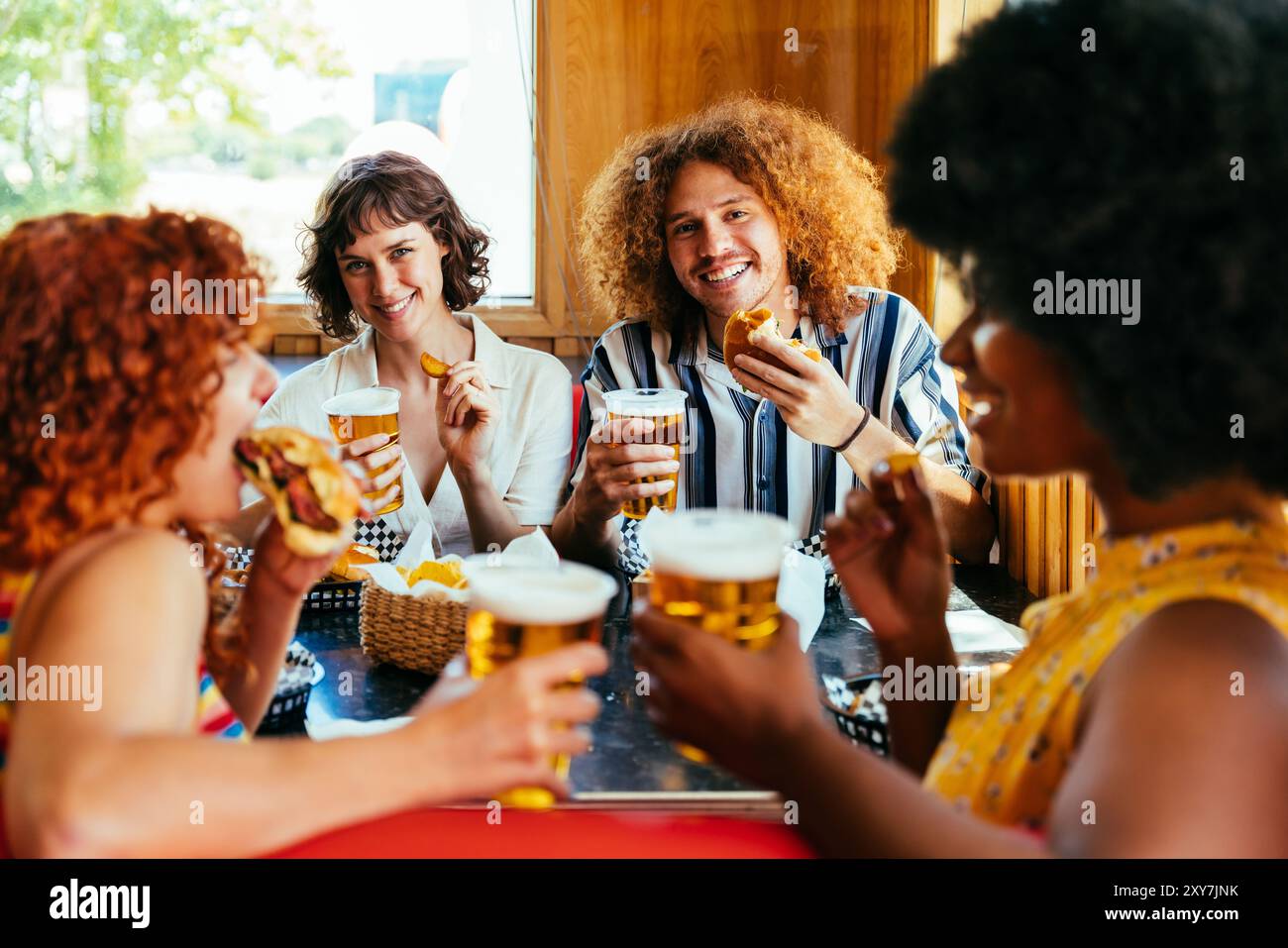 Multiethnic group of friends having meal at 80s vintage diner ...