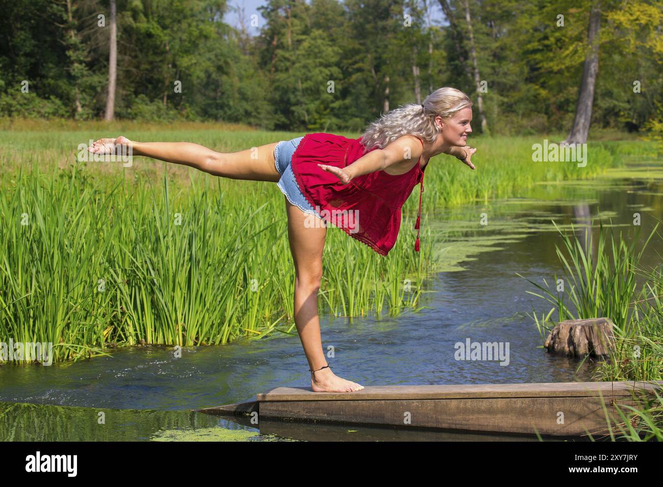 Young blond woman in yoga posture on one leg in nature Stock Photo - Alamy