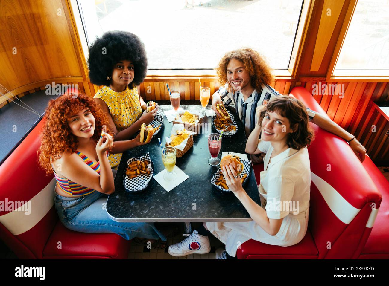 Multiethnic group of friends having meal at 80s vintage diner ...