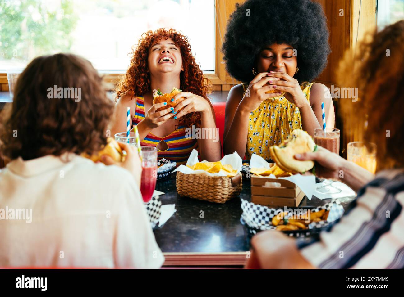 Multiethnic group of friends having meal at 80s vintage diner ...