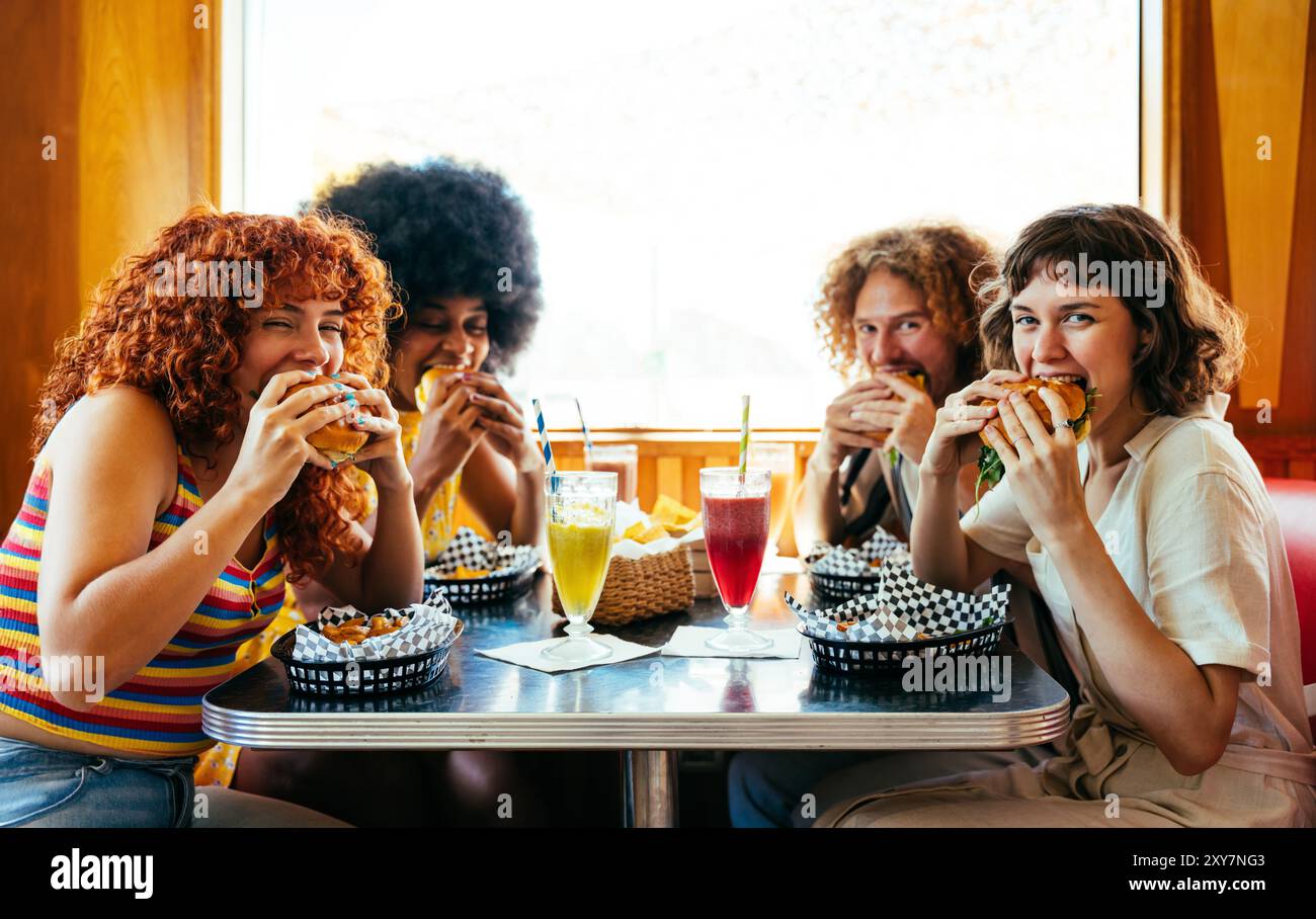 Multiethnic group of friends having meal at 80s vintage diner ...