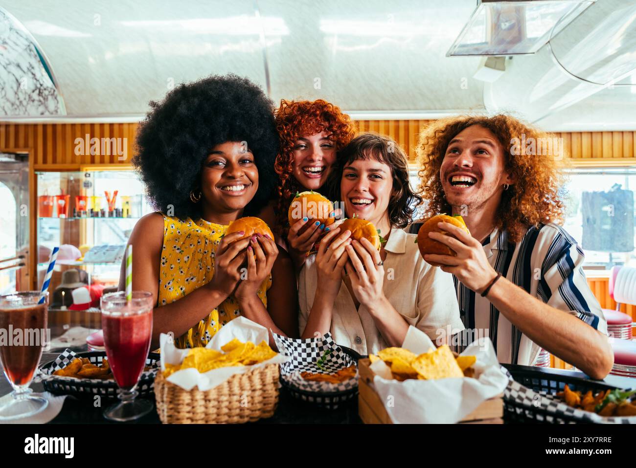 Multiethnic group of friends having meal at 80s vintage diner ...
