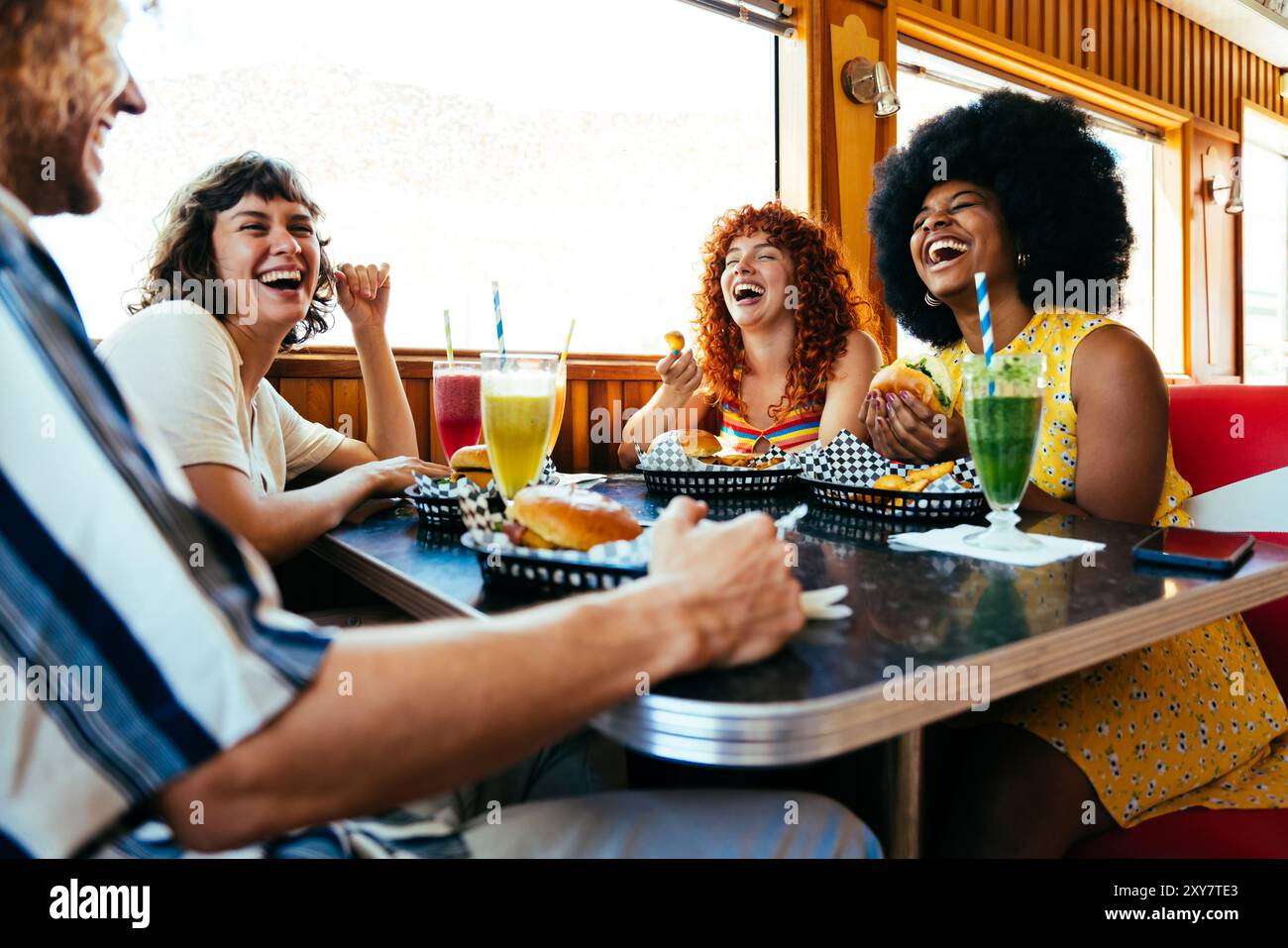 Multiethnic group of friends having meal at 80s vintage diner ...