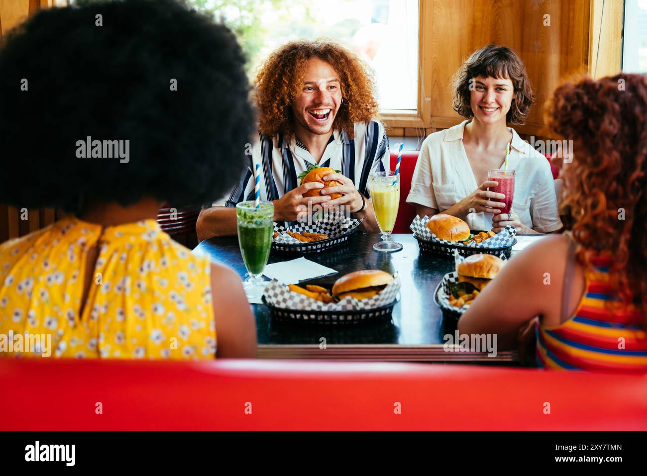 Multiethnic group of friends having meal at 80s vintage diner ...