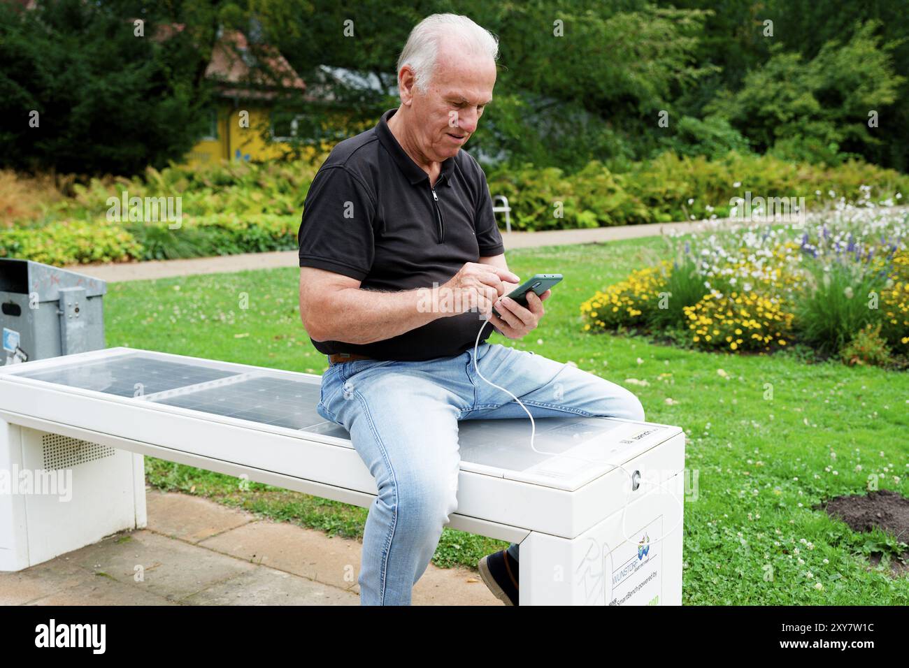 Man sitting on a Smart Bench and charging his mobile phone, bench with ...