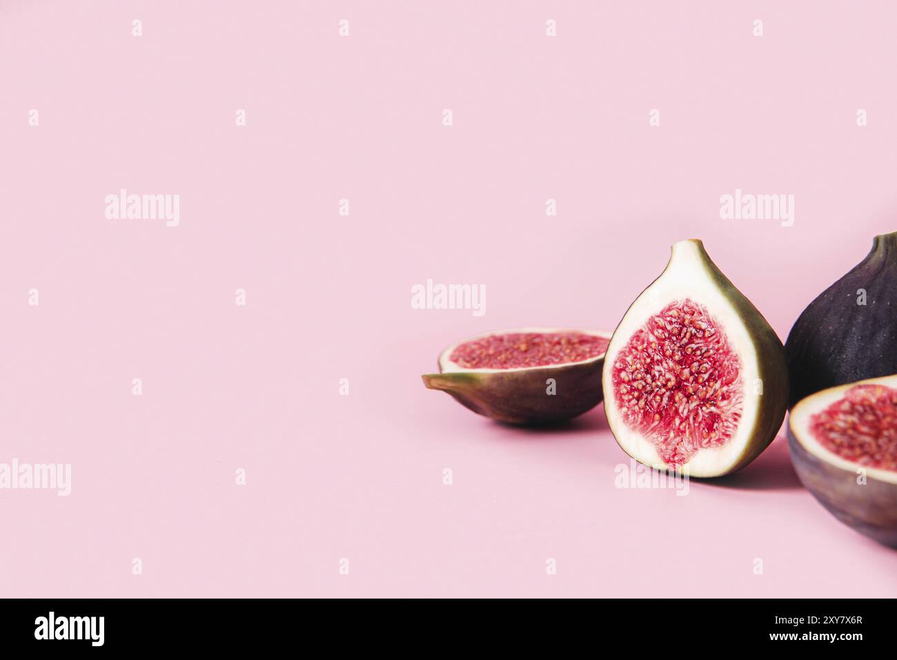 Fresh tasty fig fruit halves with shadow on pink background table with ...