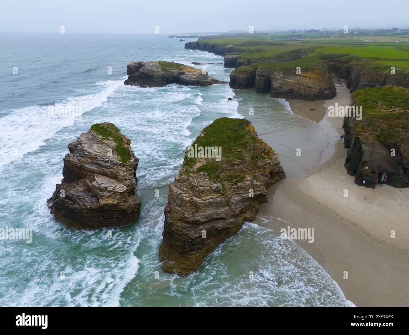 Gigantic, jagged rocks jutting out of the sea and lapped by foaming ...