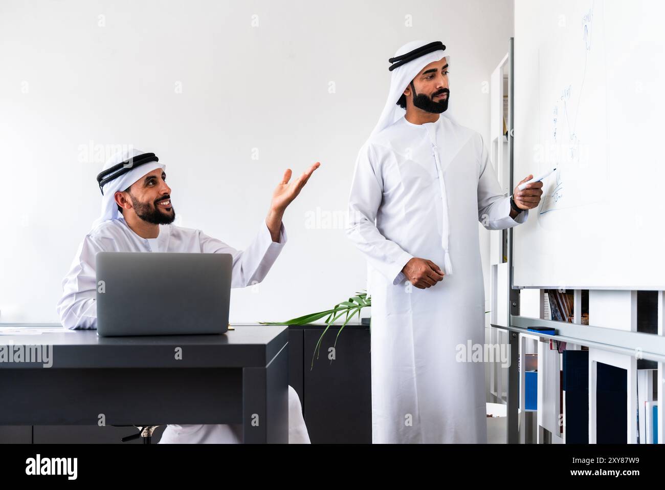 Arab men wearing traditional emirate clothing working in the office ...