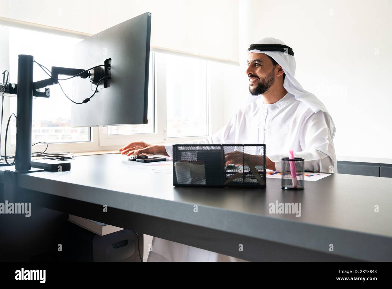 Arab man wearing traditional emirate clothing working in the office ...