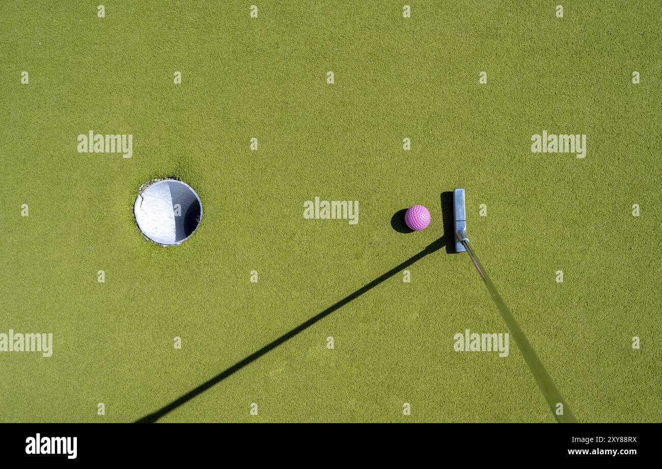 Pink golf ball by a hole on a mini golf course Stock Photo - Alamy