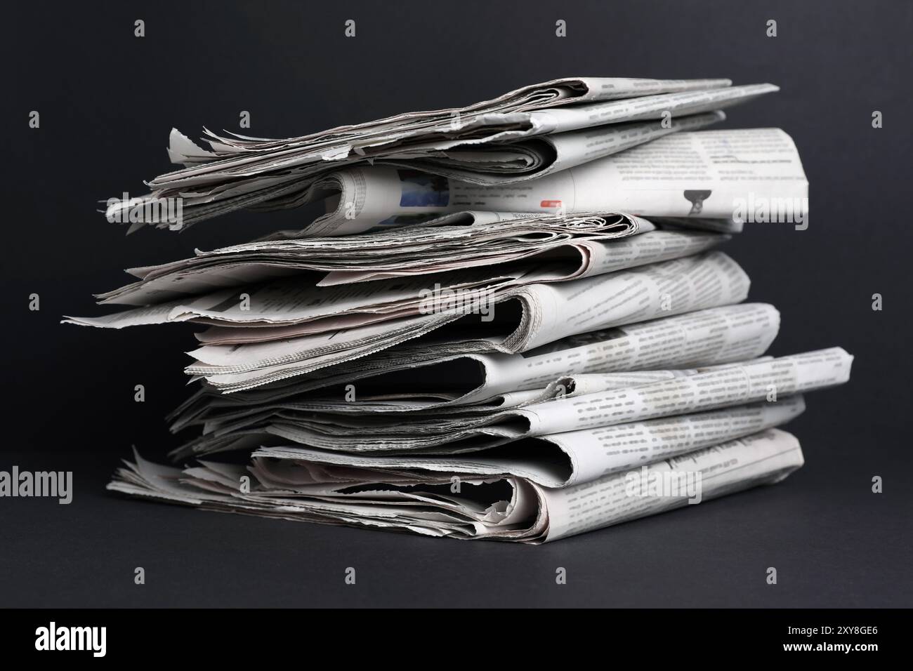Stack of newspapers in different languages on black background, closeup ...