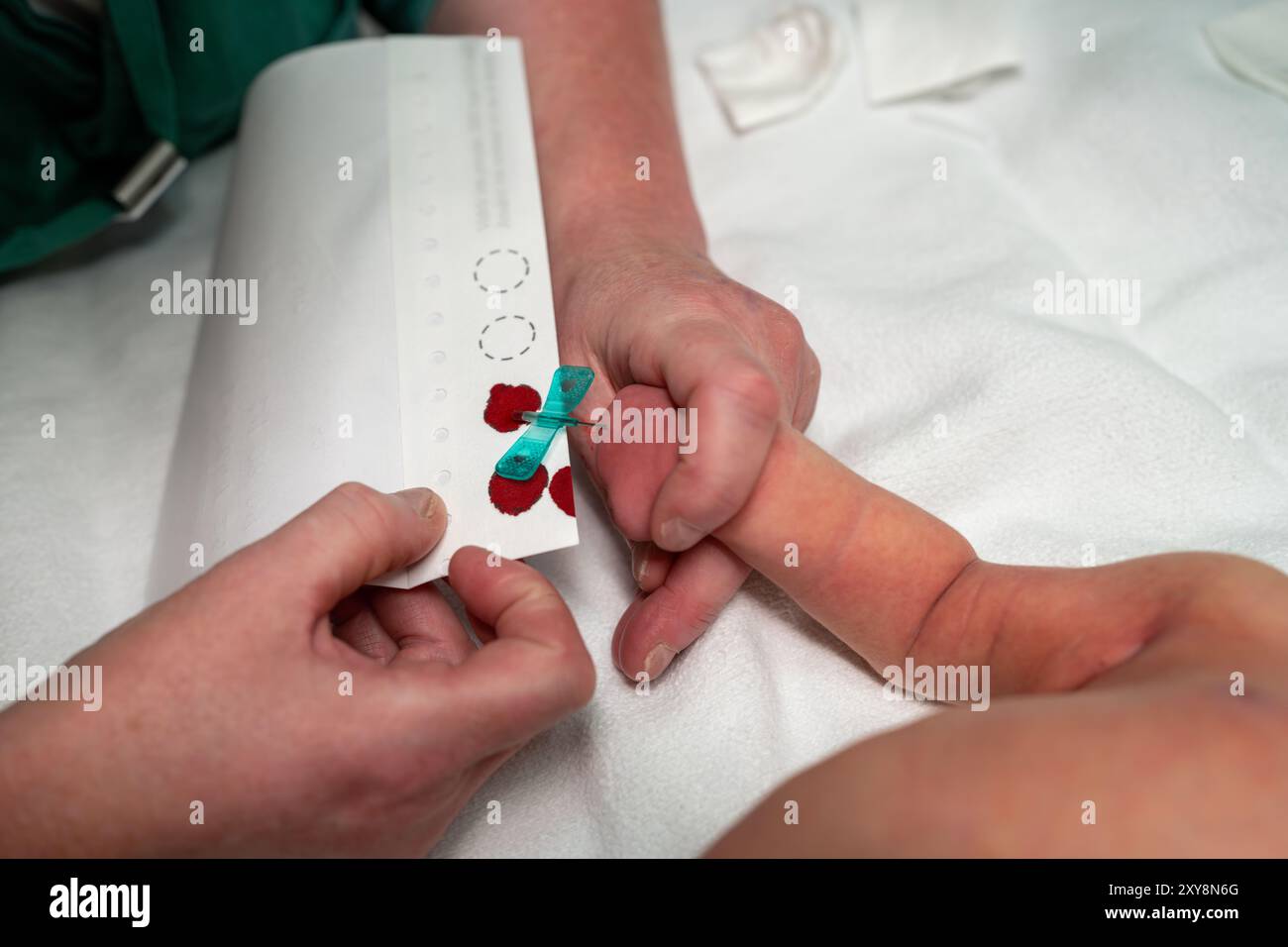 A doctor performing a blood sampling procedure on a newborn baby in a ...