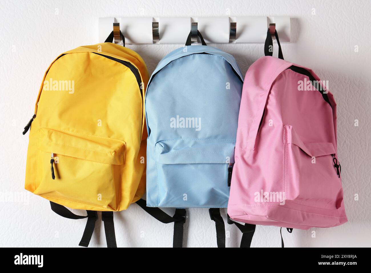 Bright backpacks hanging on white wall. Back to school Stock Photo - Alamy