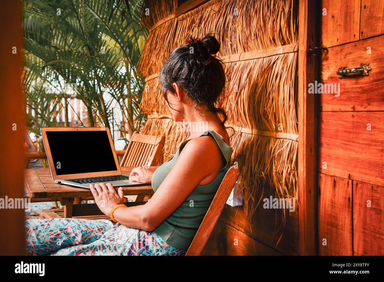 Back view caucasian hipster woman sit by computer outside eco-friendly ...