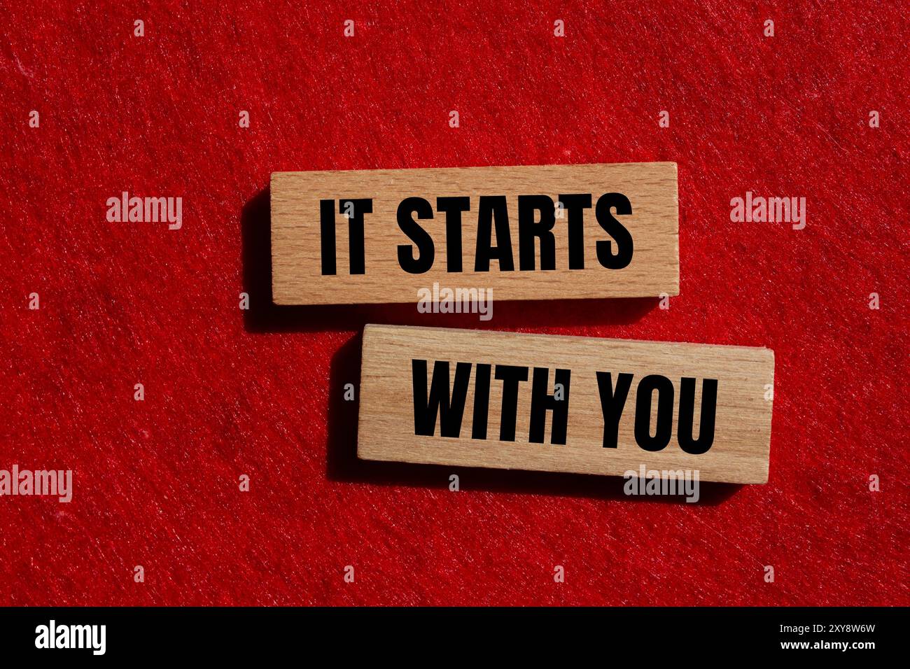 It starts with you message written on wooden blocks with red background ...