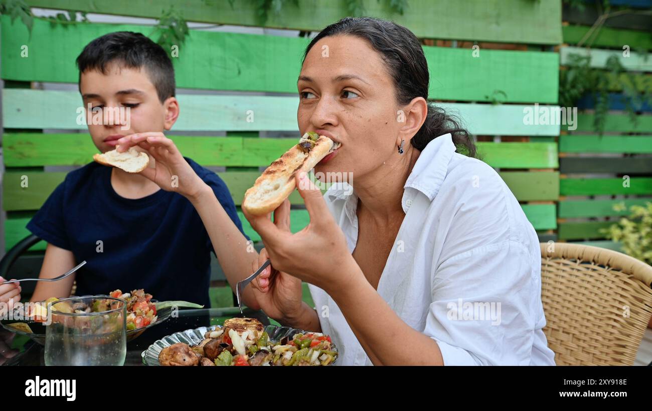 A mother and son savoring a meal outside, highlighting family bonding ...