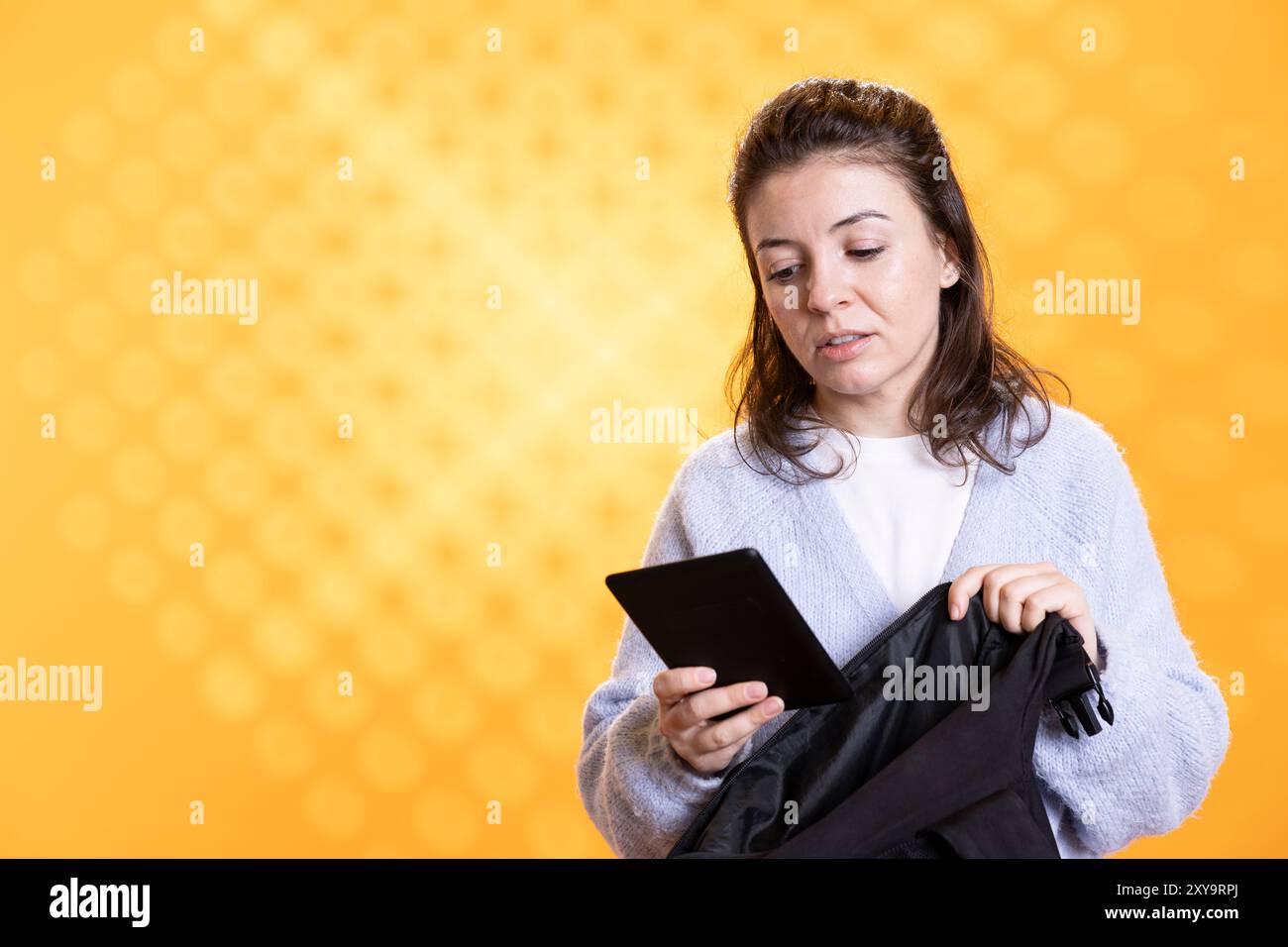 Portrait of woman rummaging through backpack, taking out tablet ...