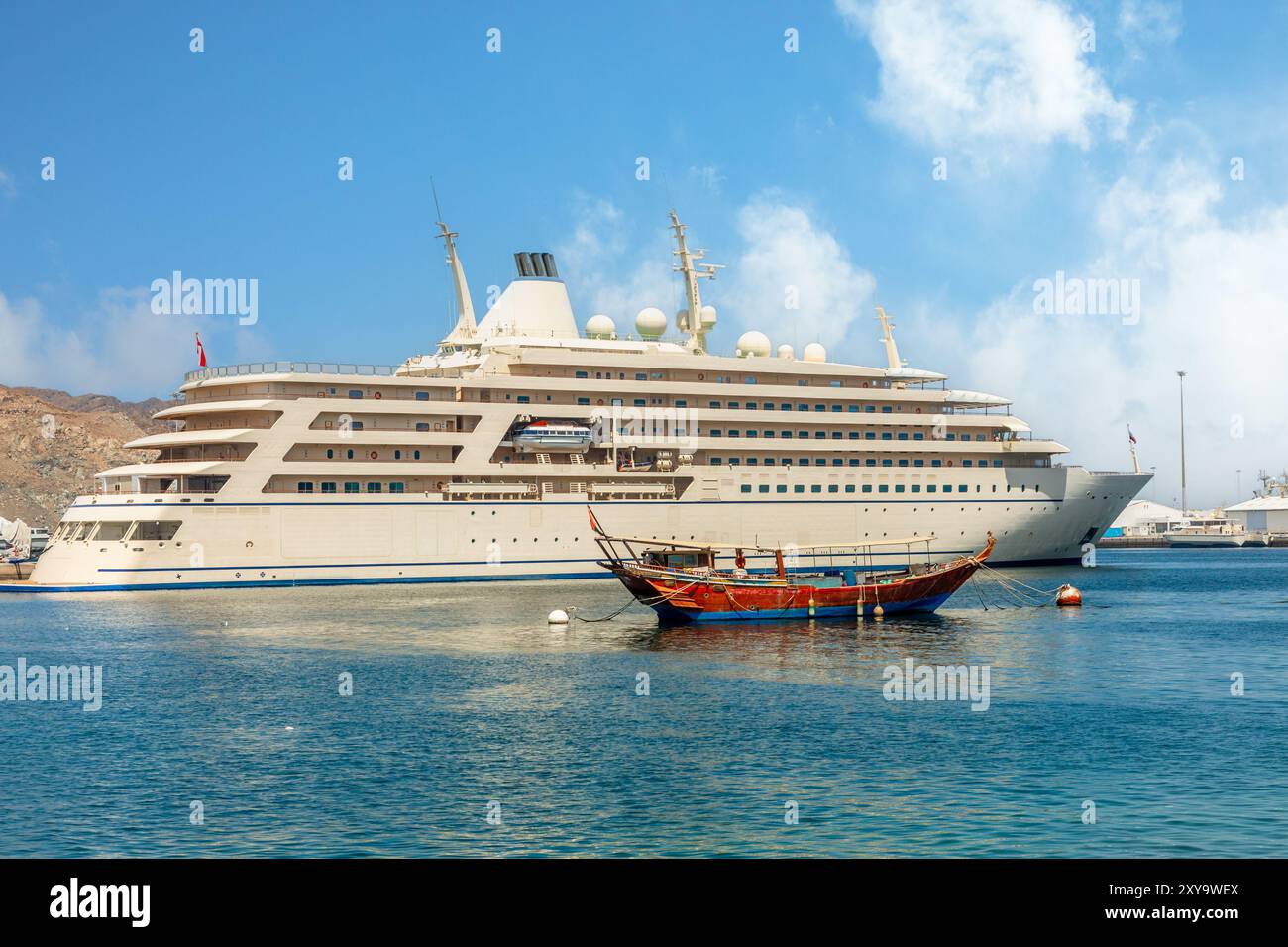 Traditional omani dhow boat with tourist cruise liner ship anchored in ...