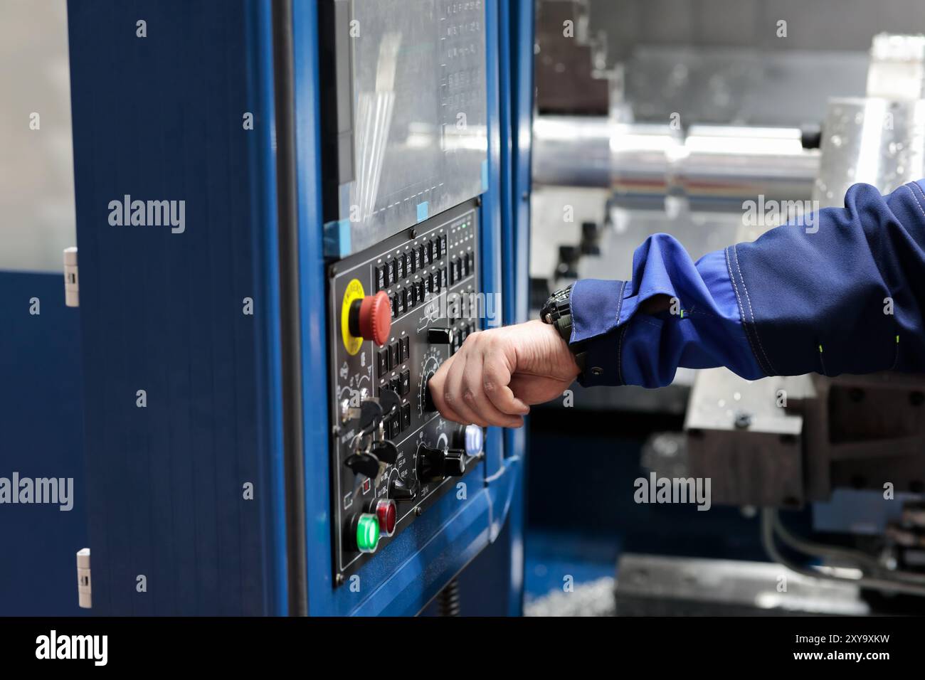 Operator controls CNC lathe machining center using control panel. Selective focus Stock Photo ...