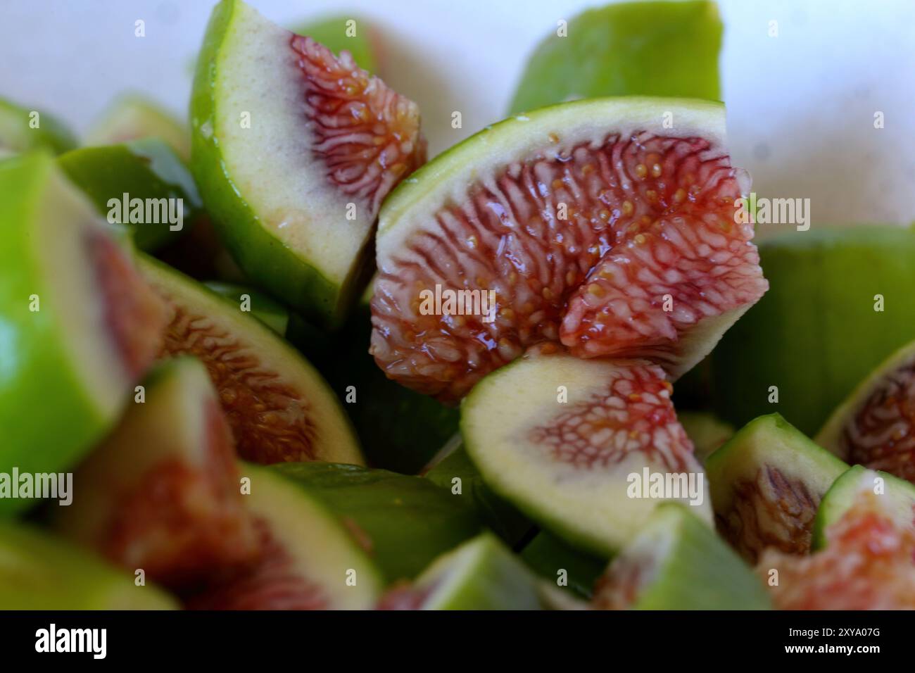 Fresh fig fruits, cut into pieces, showcasing their green outer skin ...