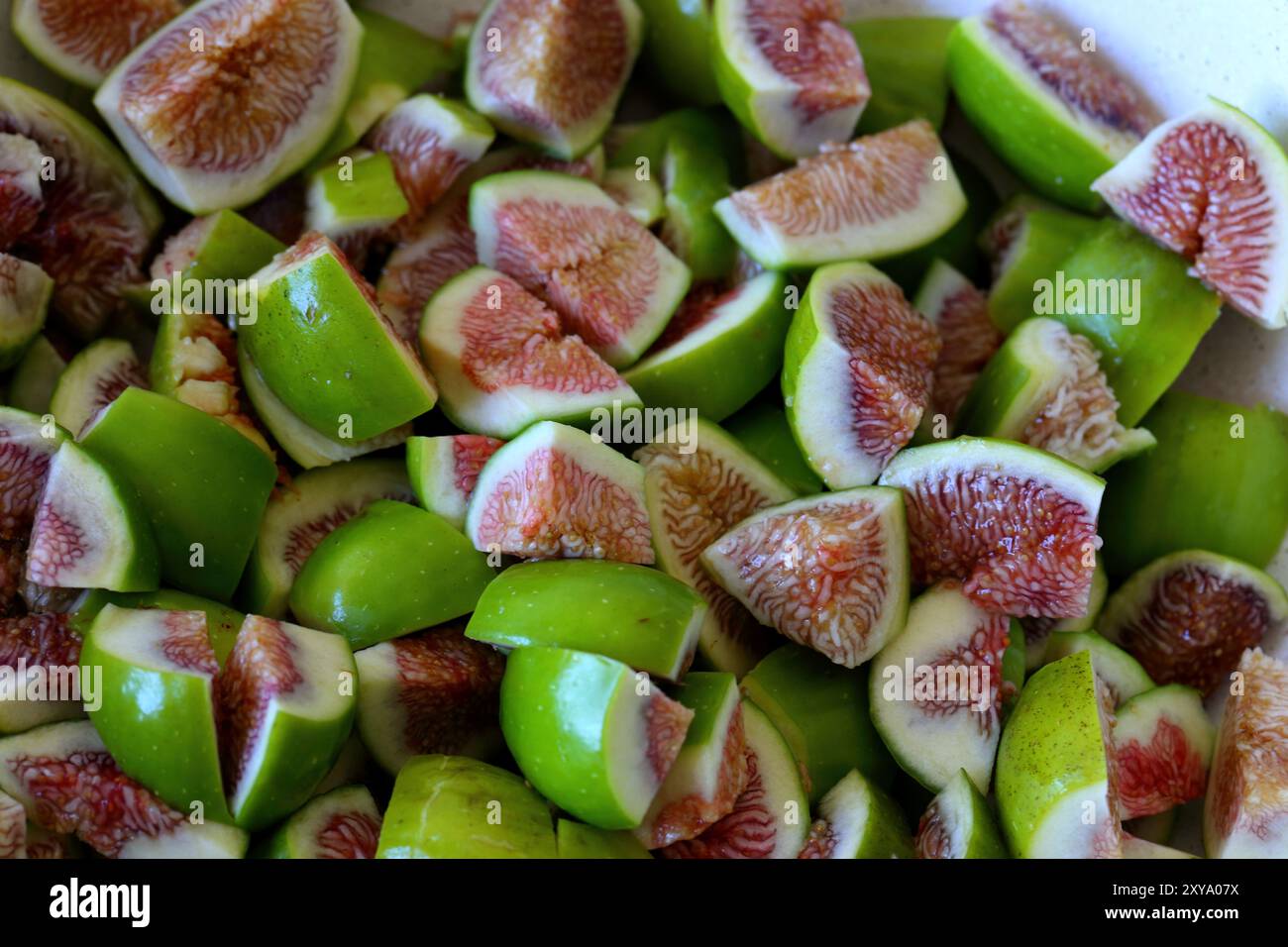 Fresh fig fruits, cut into pieces, showcasing their green outer skin ...