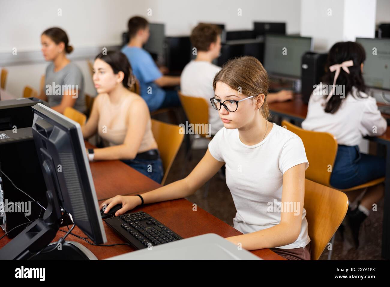 Positive female teenager in glasses learning computer science while she ...
