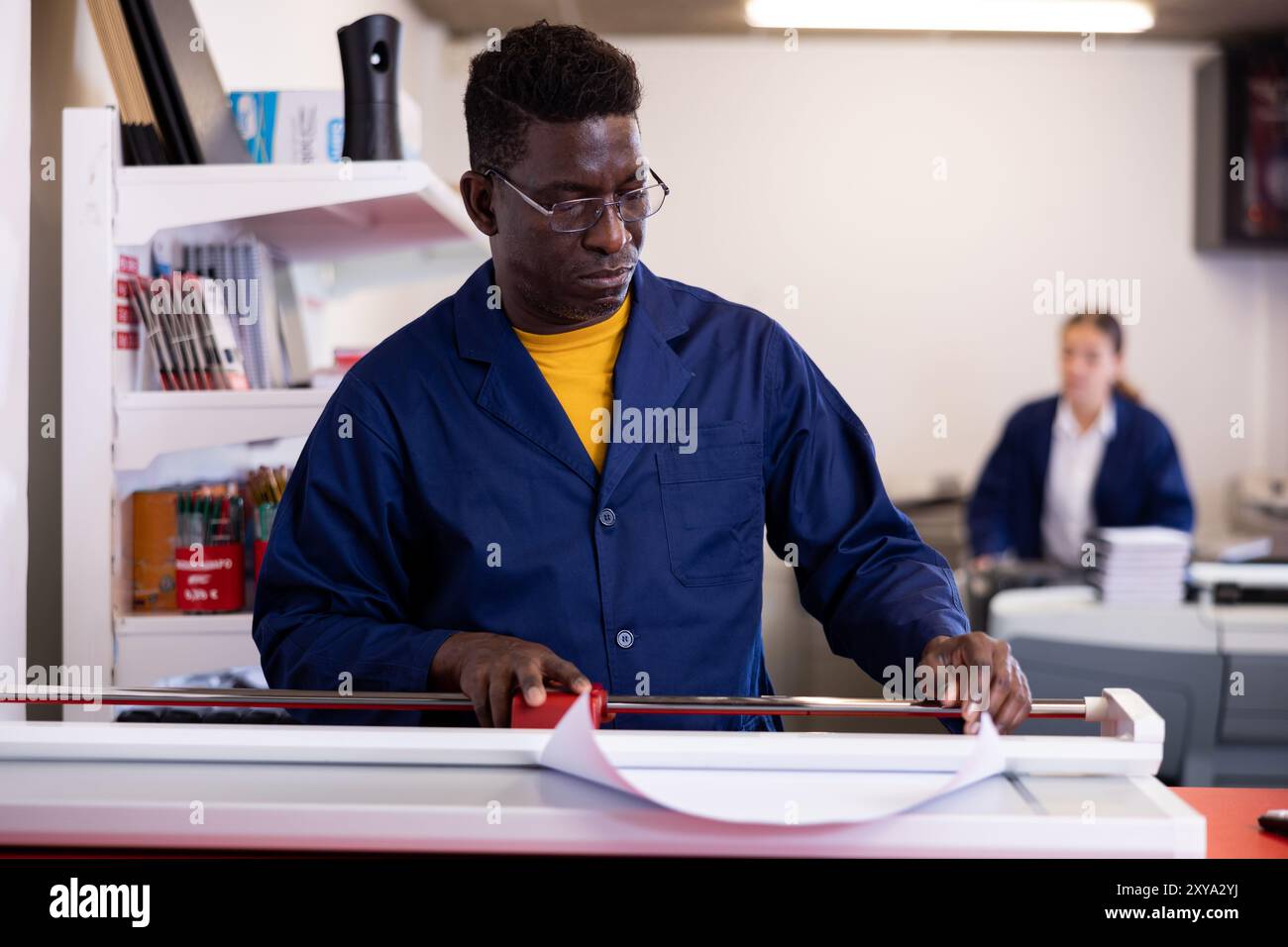 Serious print shop worker cuts paper on professional cutter Stock Photo ...