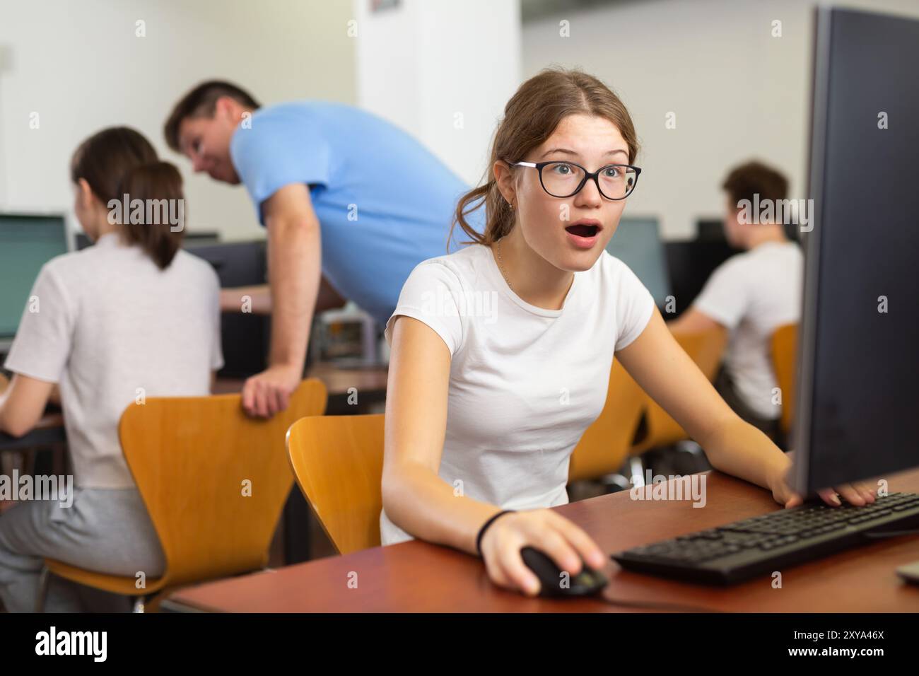 Surprised girl student sitting at her workplace and studying in computer class Stock Photo - Alamy