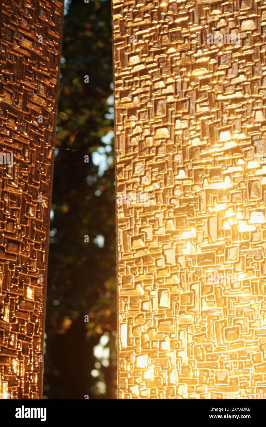 A textured glass surface catches the soft glow of sunset, featuring a ...