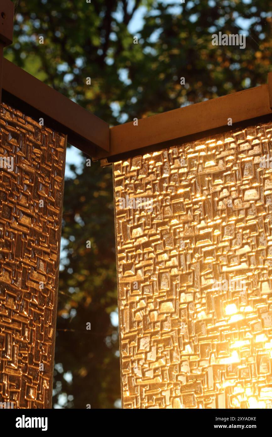 A textured glass surface catches the soft glow of sunset, featuring a ...