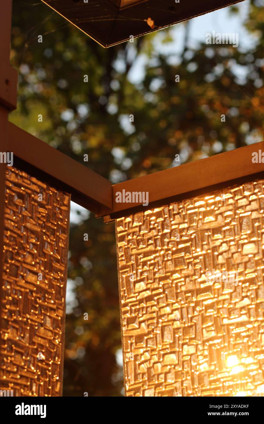 A textured glass surface catches the soft glow of sunset, featuring a ...