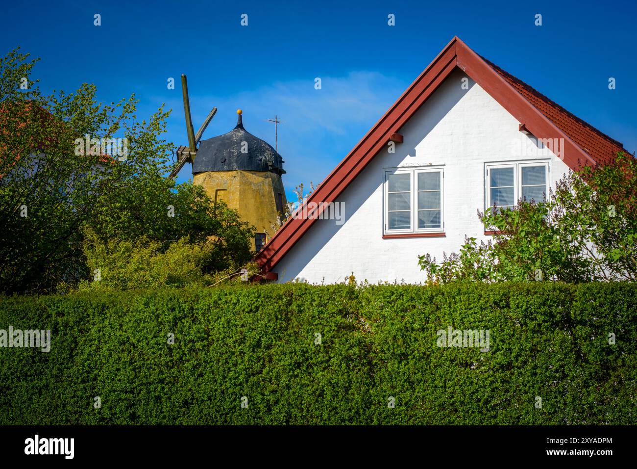 Old yellow windmill and a white house with a red sloping roof in Nexo ...