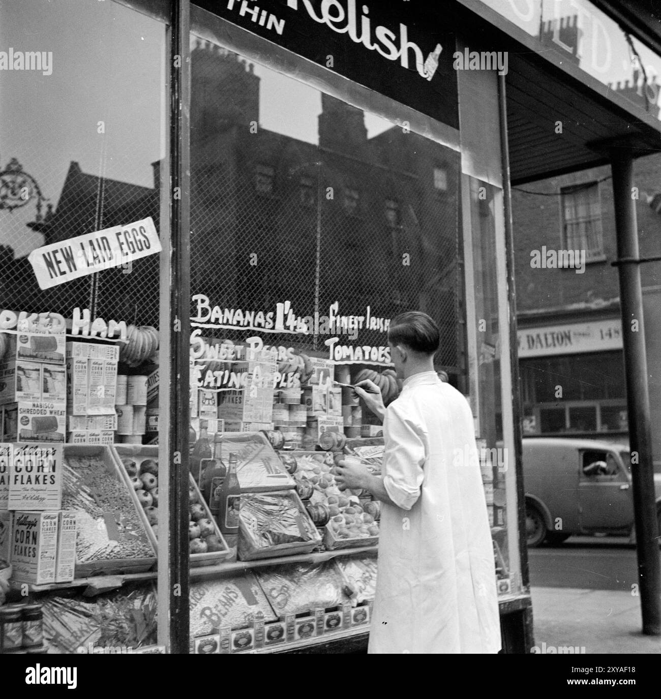 A shopkeeper paints texts on the shop window advertising produce ...
