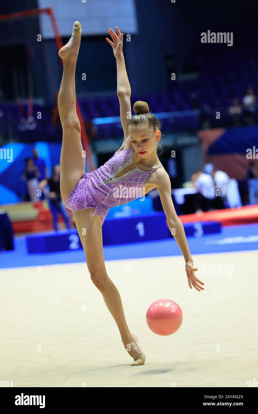 A rhythmic gymnast impresses at a competition with precise and elegant ...