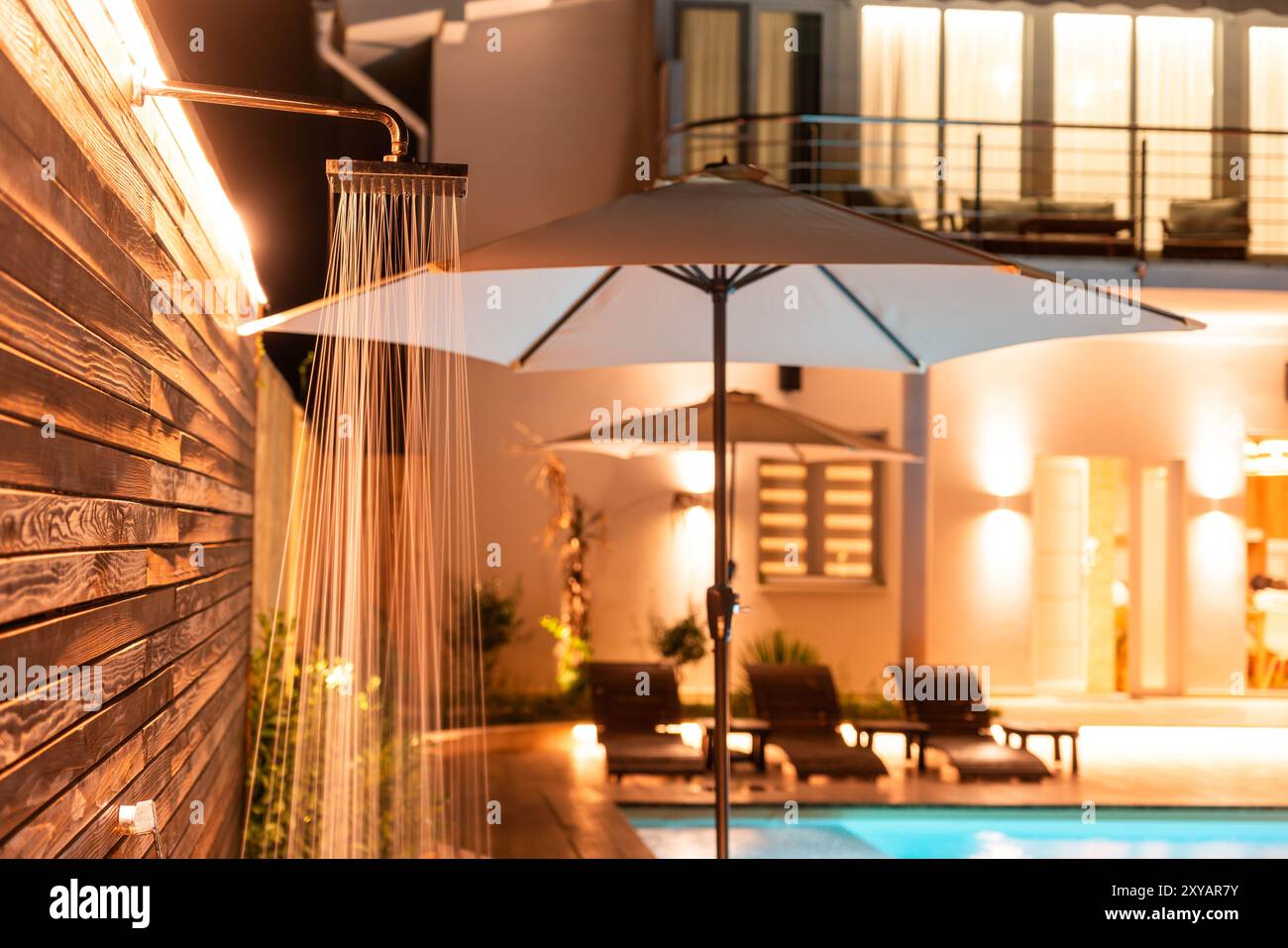 Outdoor shower with flowing water at night near swimming pool. Concept ...