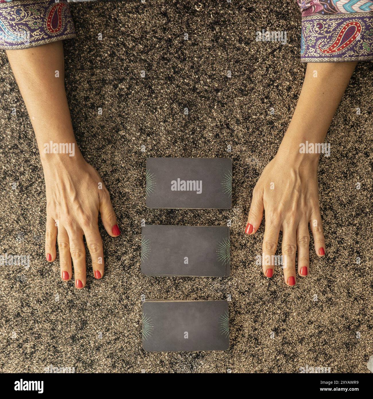 Top view of a tarot reader's hands and three cards turned face down ...