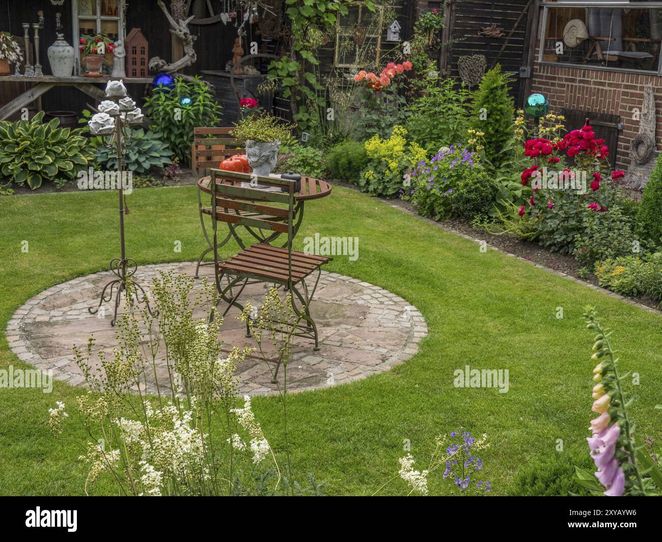 A quiet garden seating area with a metal chair and table on a paved ...