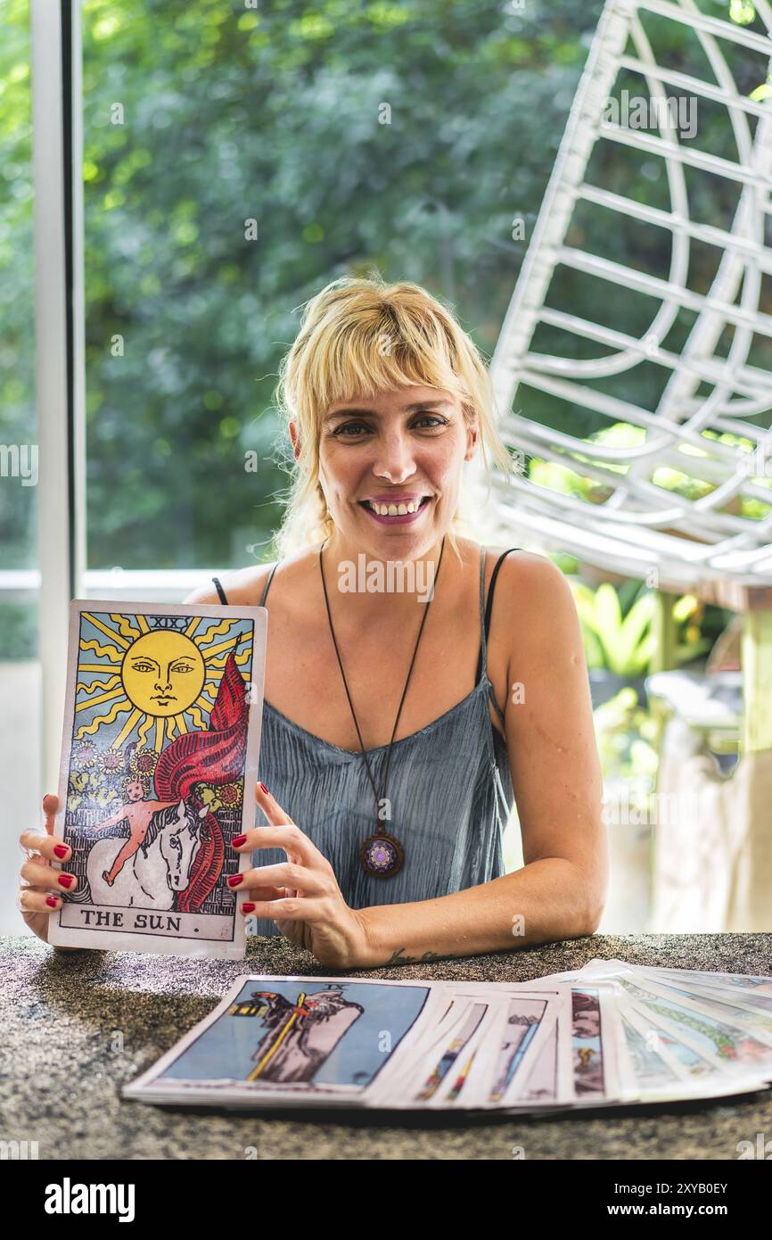 A tarot reader joyfully showing a large card of The Sun while looking ...