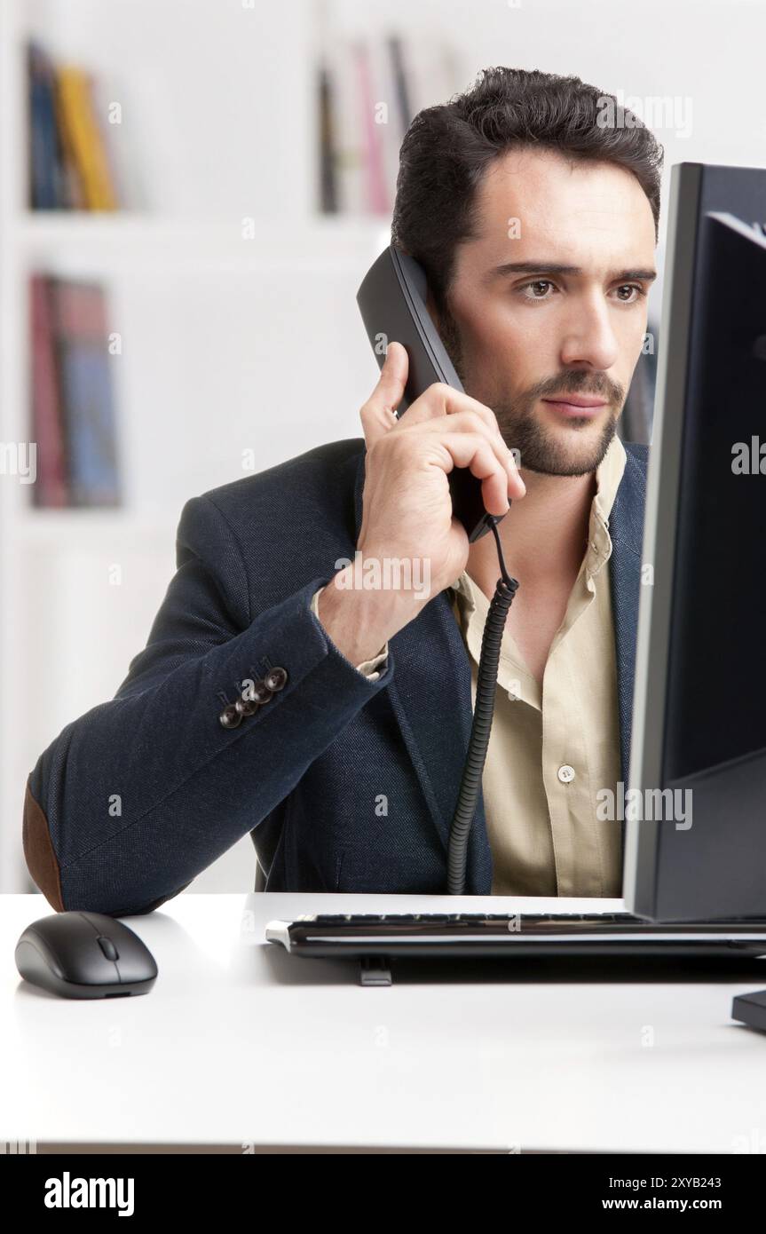 Man looking at a computer screen, on the phone, thinking about the job ...
