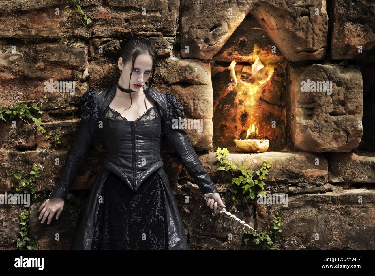 A game with the fire of a young gothic lady with dagger playing with ...