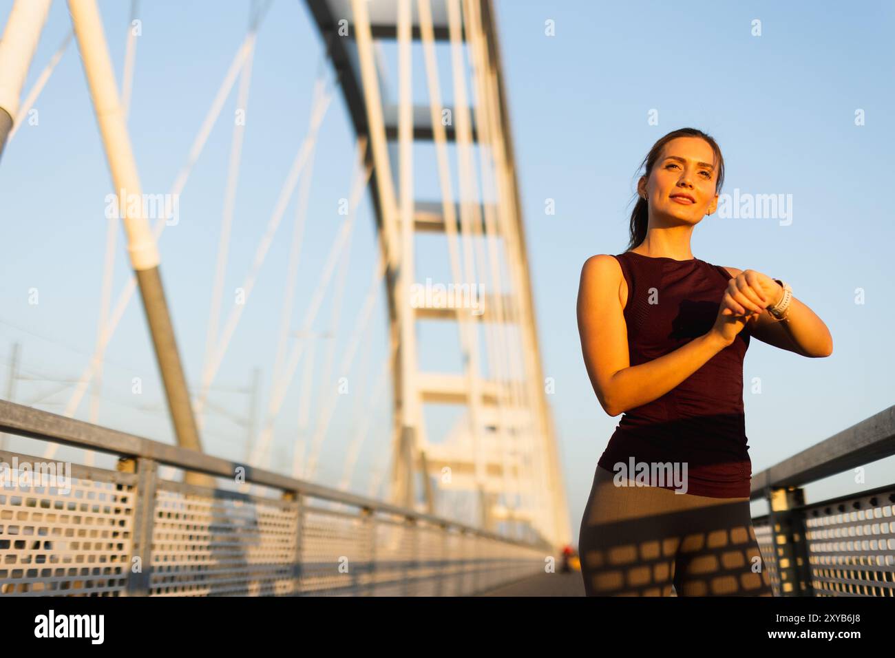 Basking in the warm glow of the sunset, a dedicated runner pauses on a bridge to check her watch ...