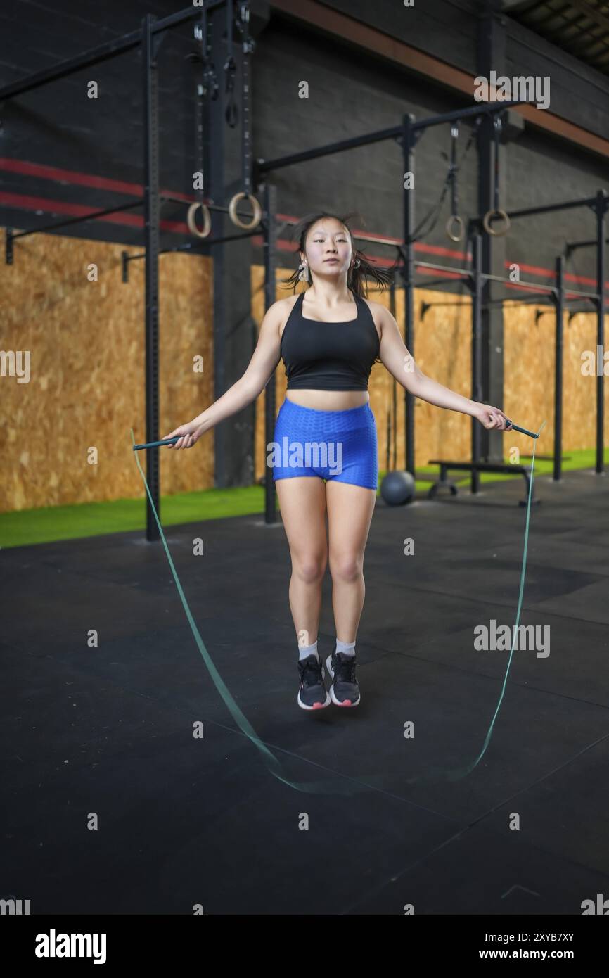 Vertical full length portrait of a Chinese strong woman skipping rope ...