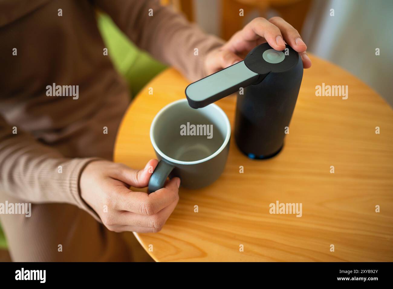A woman is holding a mug and a device for pouring water from the water ...