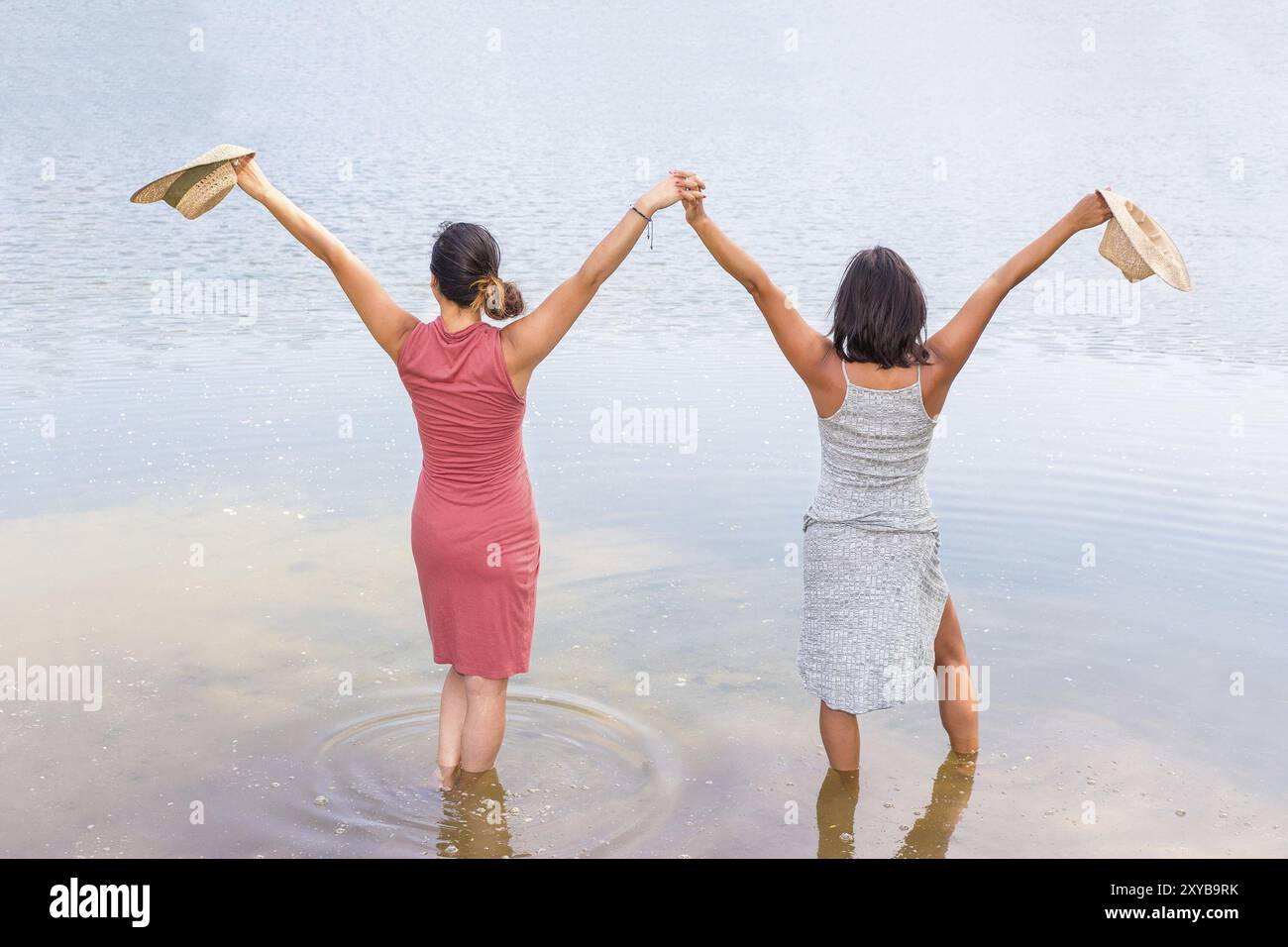 Two happy friends standing together in water of lake Stock Photo - Alamy