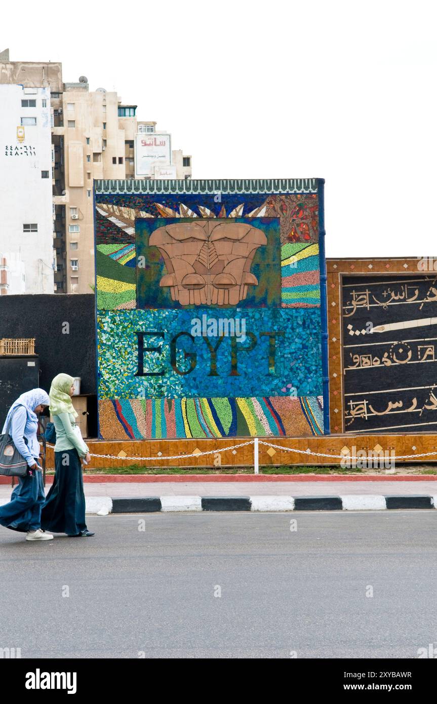 Egyptian college students walking by a colorful decorated wall in ...