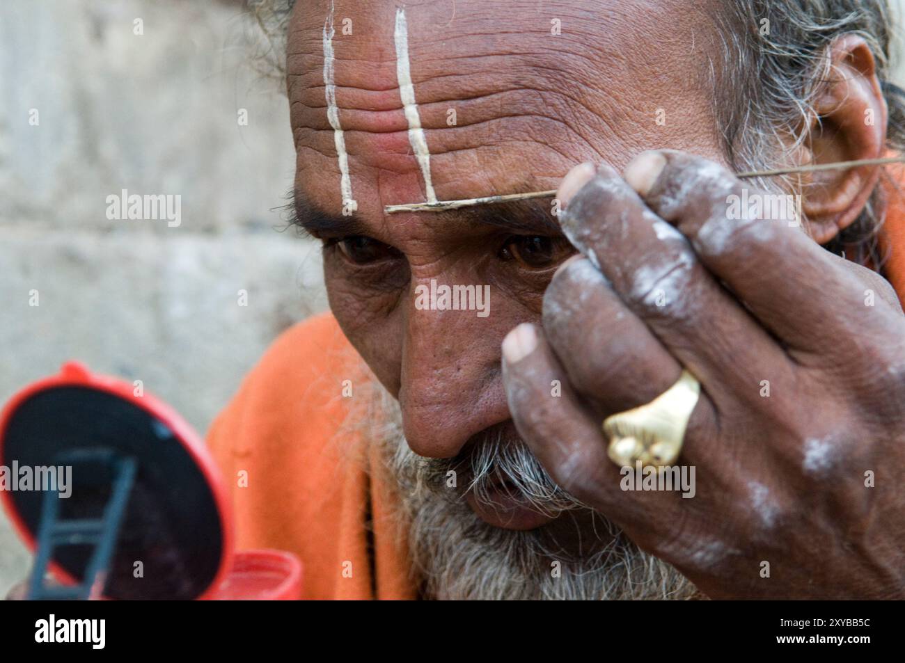 A sadhu painting his forehead with Tilaka on the Mallick Ghat by the ...
