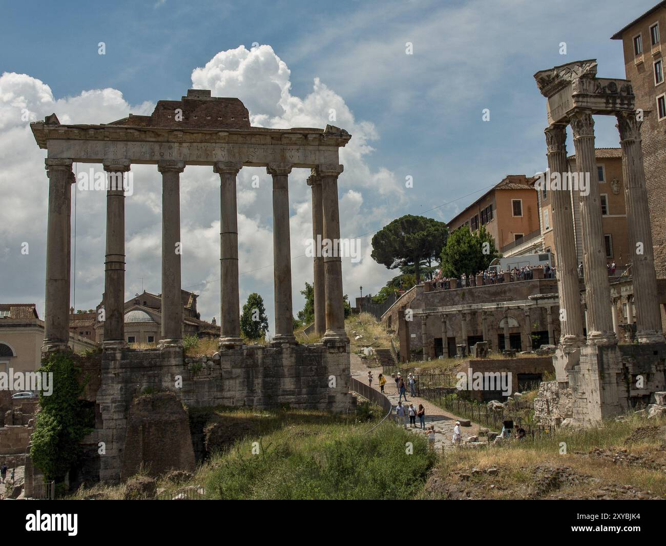 Ancient temple ruins with tall columns and tourists, under a blue sky ...