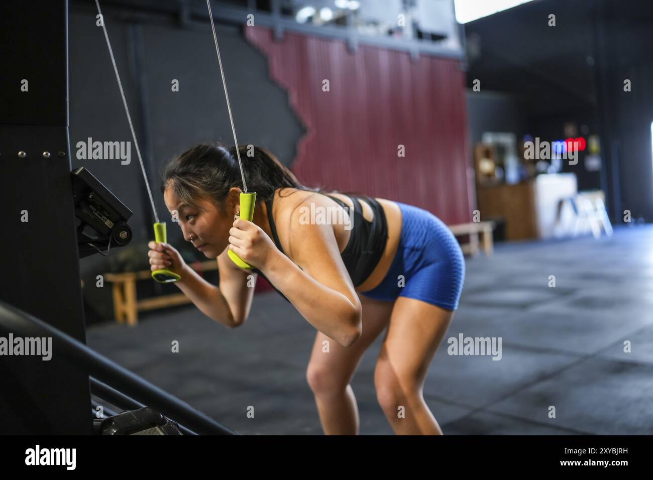 Side view of a Chinese woman exercising using lat machine pulling ...