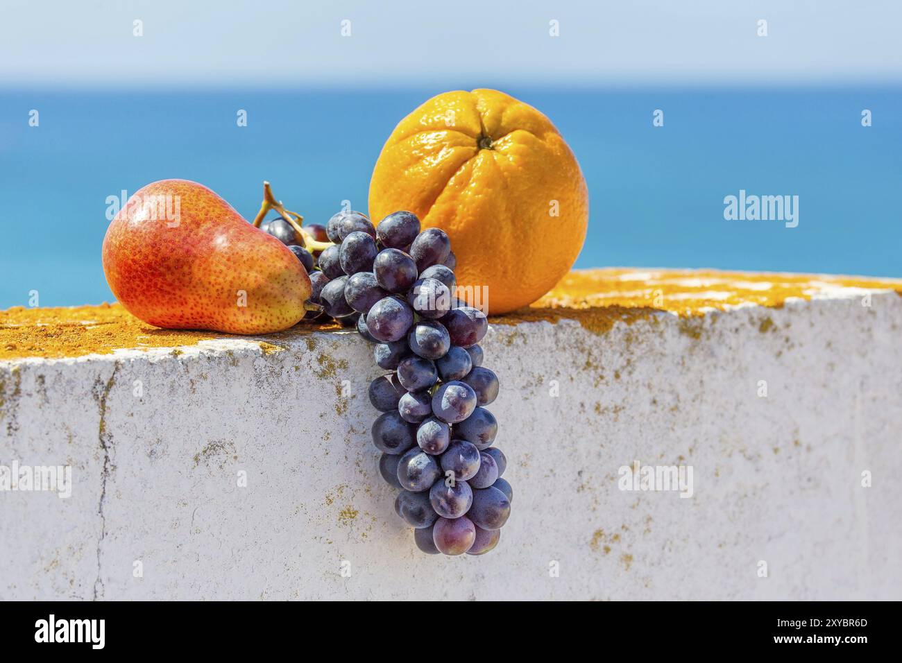 Grapes orange and pear lying on wall with sea and sky Stock Photo - Alamy